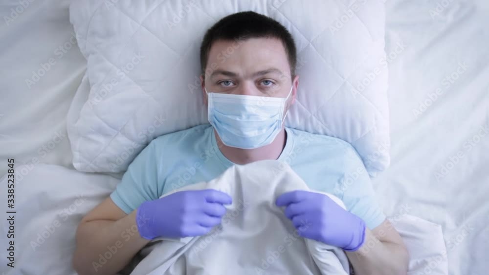 Sick man wearing medical facial mask lying down in bed wearing ...