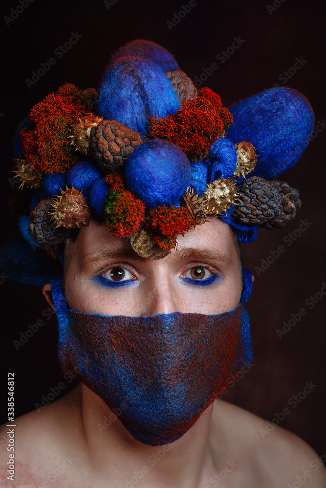 Male model with an egg - shaped headdress made of cones. Model with a ...