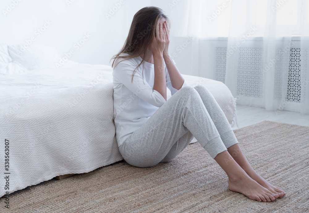 Young girl spending afternoon sitting on bedroom floor, crying because ...