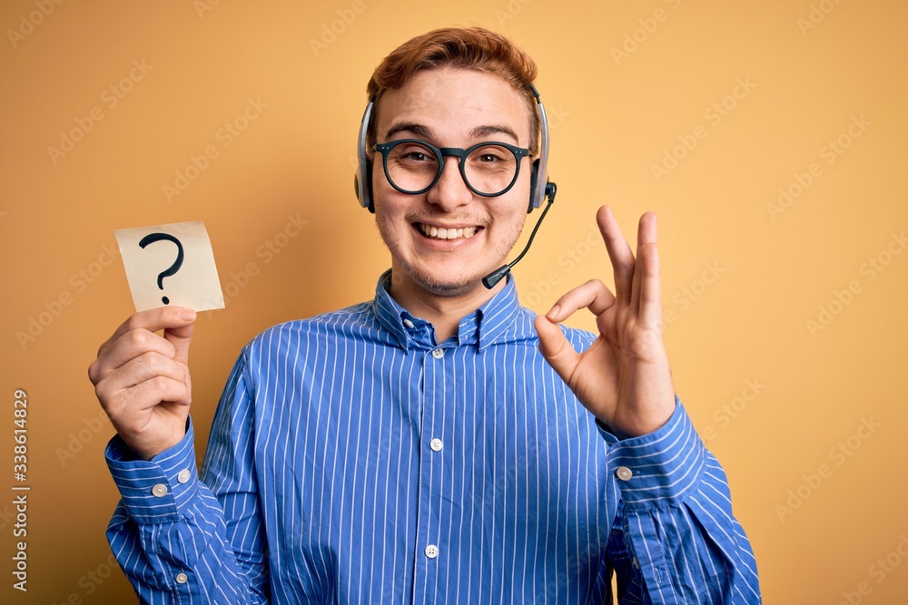 Redhead call center agent man working using headset holding reminder ...