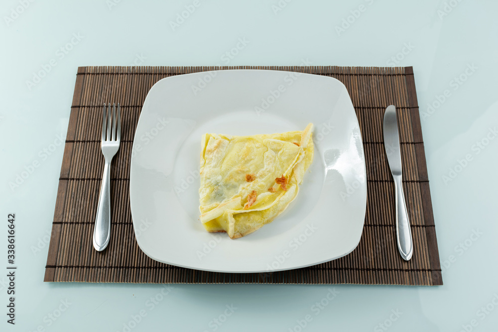 Crepioca with cheese filling next to fork and knife (Brazilian recipe ...