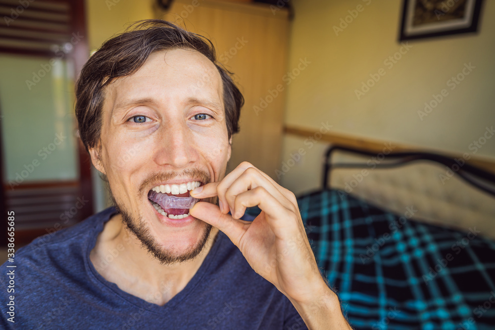 Man placing a bite plate in his mouth to protect his teeth at night ...