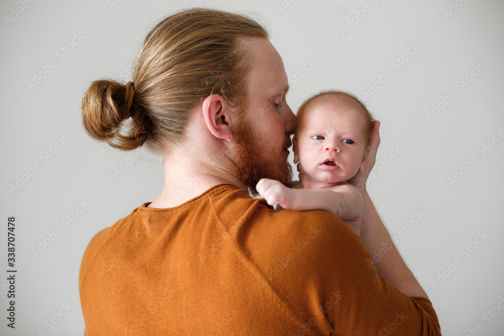 Portrait of young bearded Caucasian father hugging and kissing newborn ...