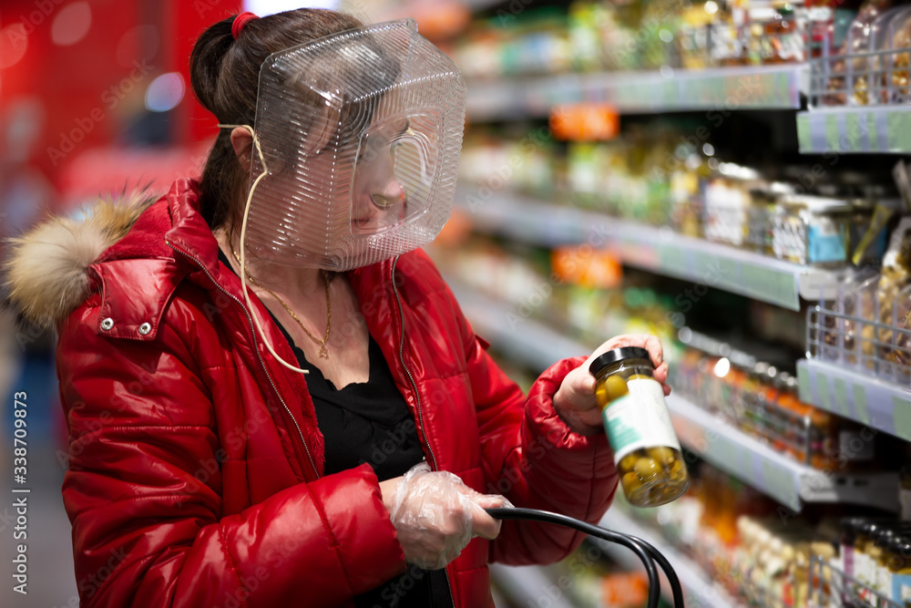 Coronovirus protection. Woman in a store with a plastic box on her face ...