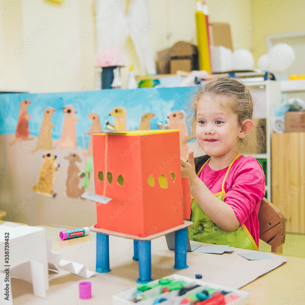 Craft lesson in kindergarten. Model of paper house glued out of paper ...