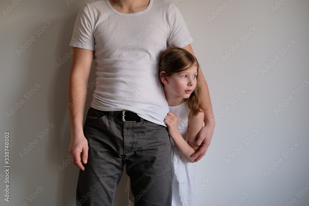 scared little girl hiding behind her dad. Daughter seeks protection ...