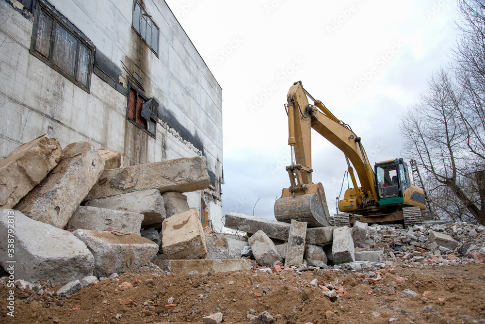 Yellow excavator with bucket at demolition of tall building. Hydraulic ...