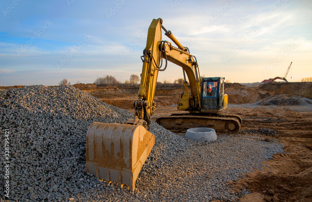 Excavator during earthmoving work at open-pit mining on blue sky ...