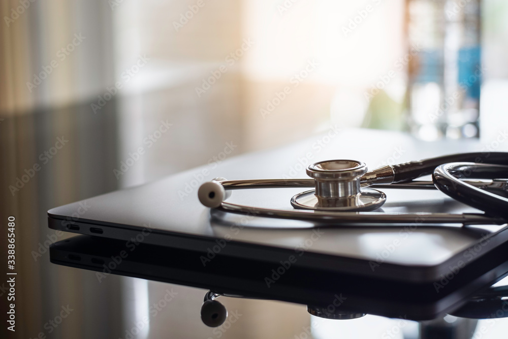 Mockup medical stethoscope and laptop computer isolated on dark table ...