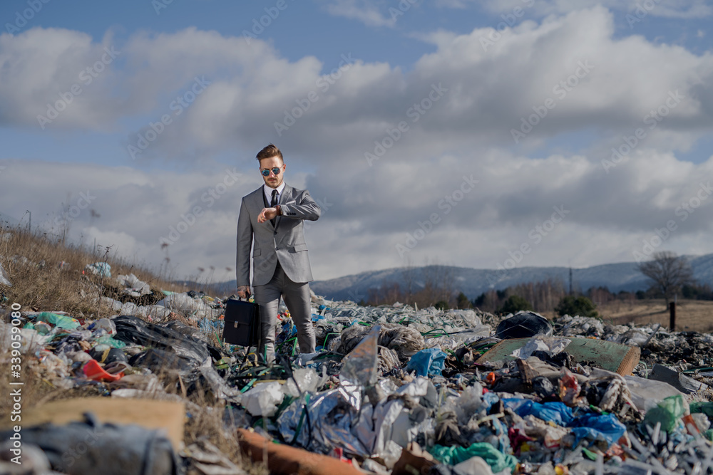 Modern businessman on landfill, consumerism versus pollution concept ...