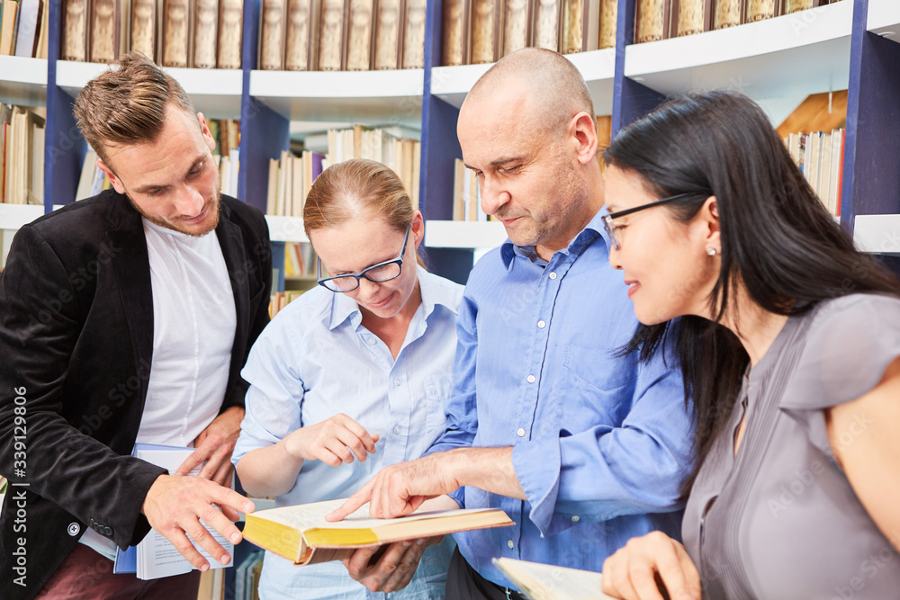 Group of people researching together in a book Stock Photo | Adobe Stock
