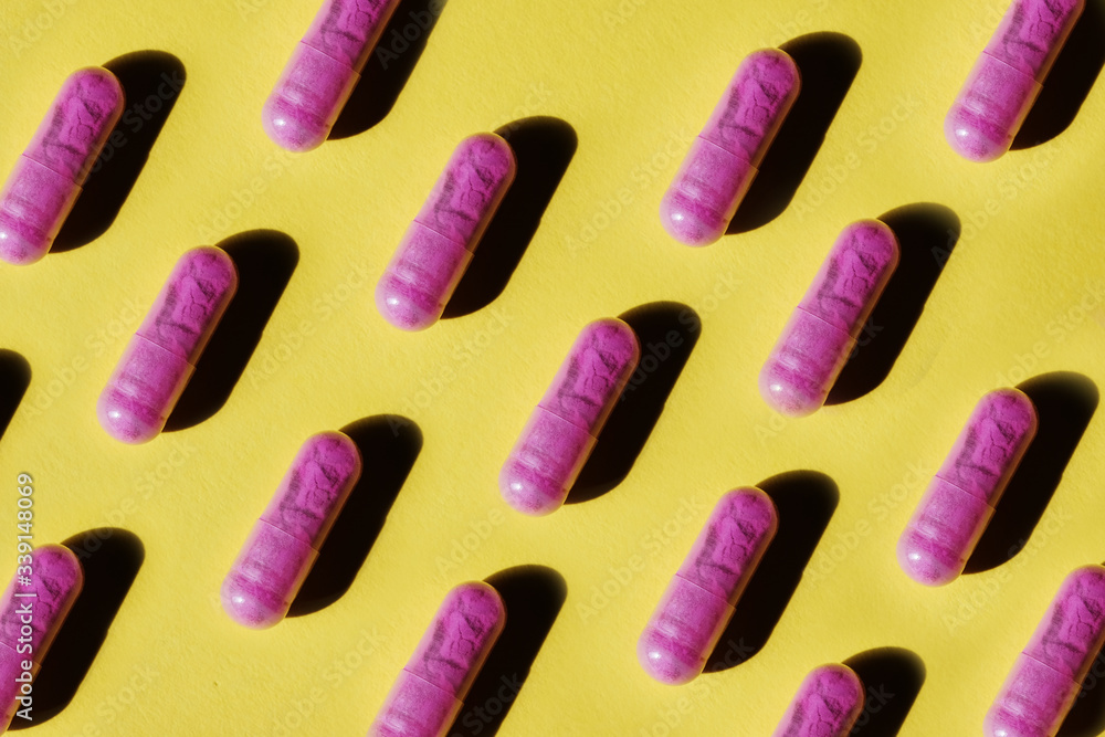 Pattern of purple pill capsules on a yellow background. Background and ...