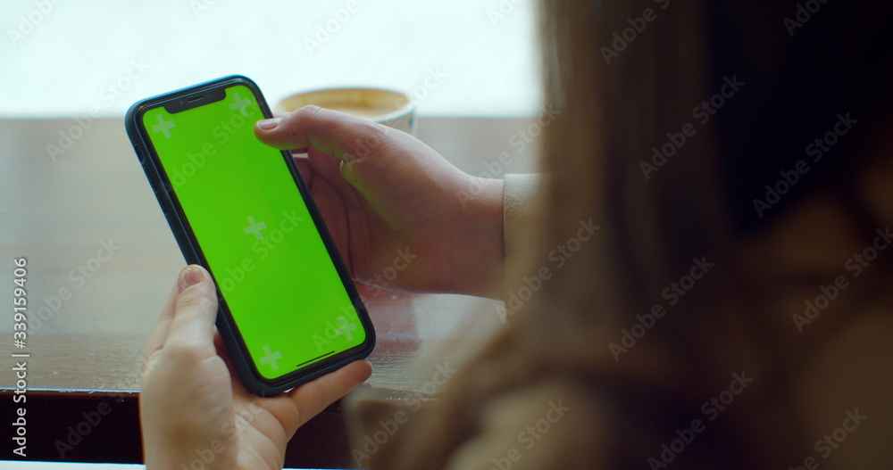 Businesswoman using mobile cell phone with green touch screen in cafe ...