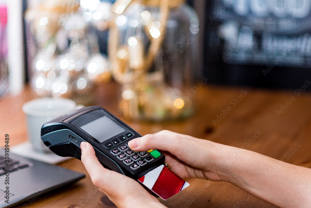 Cropped view of hand entering secure pin code on terminal to pay for ...