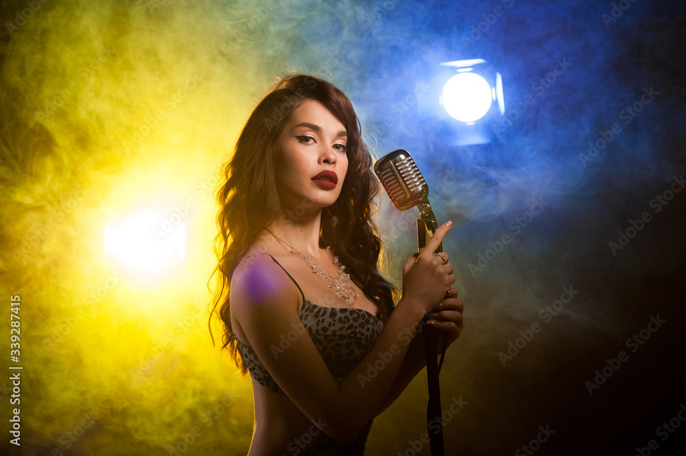 Beautiful girl singer on stage in smoke sings into a microphone Stock ...