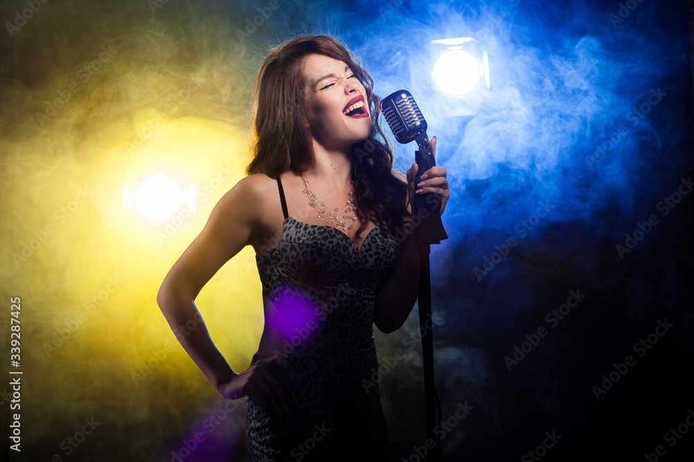 Beautiful girl singer on stage in smoke sings into a microphone Stock ...