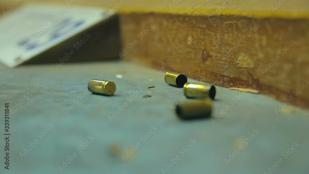 Empty pistol bullet shells dropping and impacting wooden table in a ...