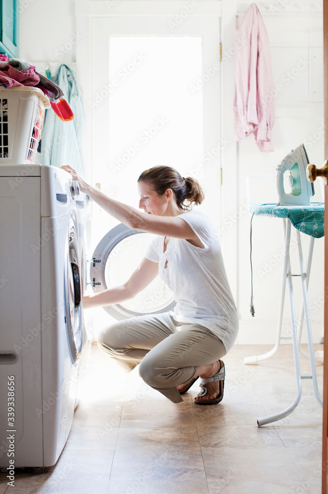 Candid picture of woman keeping things clean, doing laundry at home ...