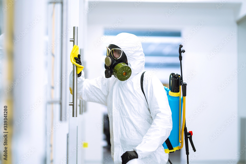 Man in protective hazmat suit washes door handles in office to ...