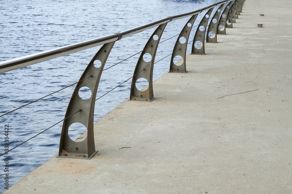 Fragment of river embankment with concrete pavement, modern metal ...