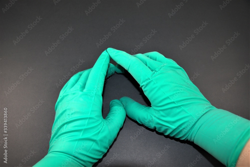 Human hands wearing sterile surgical gloves isolated on black ...