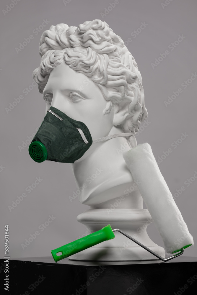 White plaster statue of a bust of Apollo Belvedere in a mask respirator ...