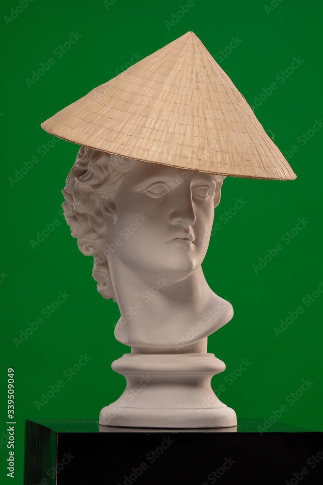 Statue of a bust of Apollo Belvedere in an Asian conical hat Stock ...