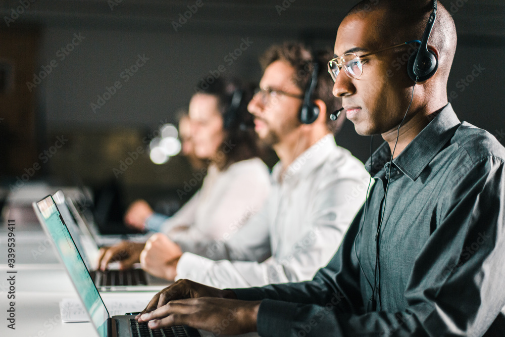Side view of concentrated call center operator working. Thoughtful call ...