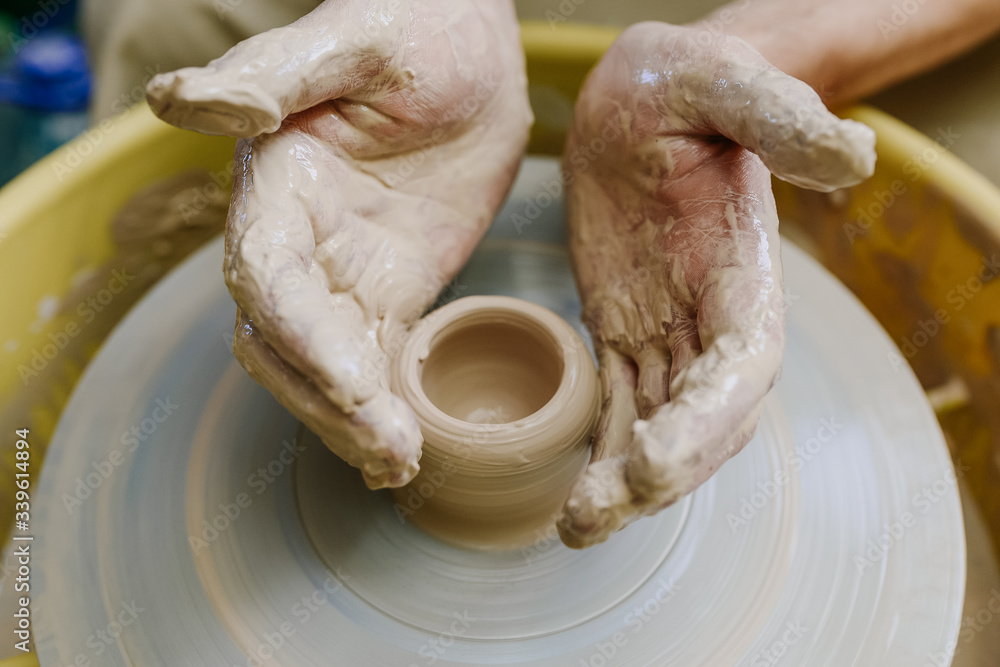 hands make a vase behind a potter's wheel. ceramics. pottery, macro ...