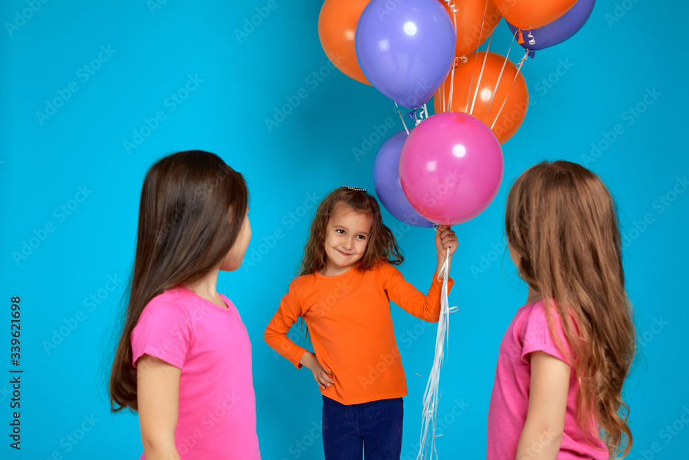 Smiling little children girls posing with bright colorful air balloons ...