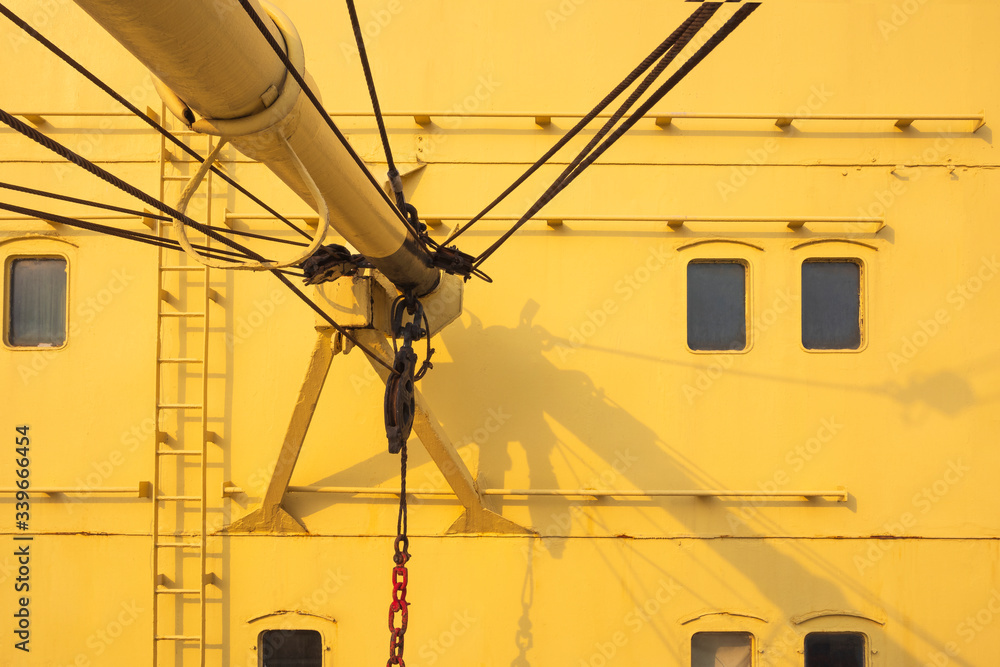 Part of the old boom crane with rusty hoist and wire rope sling in ...