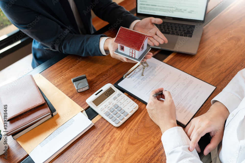 Real Estate broker or sale agent giving consultation to customer about buying house sign ...