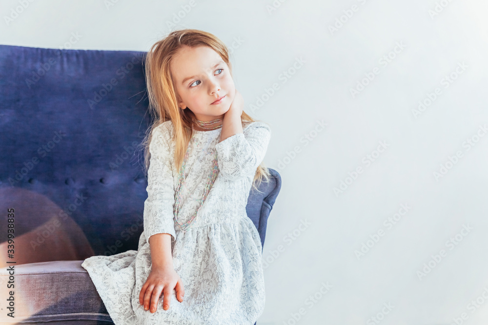 Stay Home Stay Safe. Sweet little girl in white dress sitting on modern ...