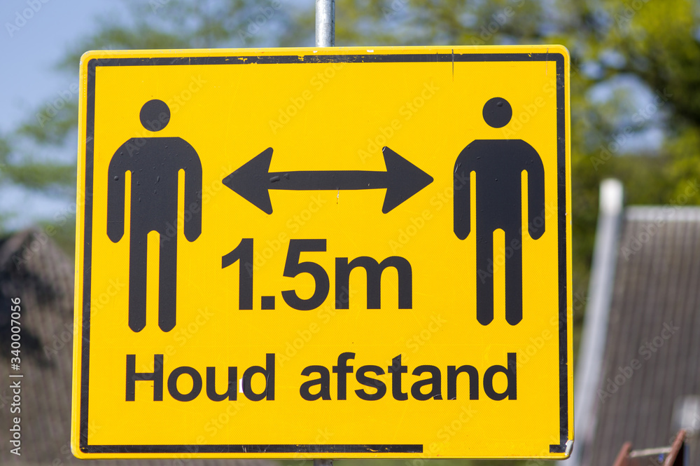 Yellow warning sign with the text in dutch: 1.5 meter, keep distance ...