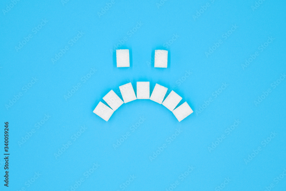 Sad face symbol, composed of cubes of sugar. Concept of sugar leading ...