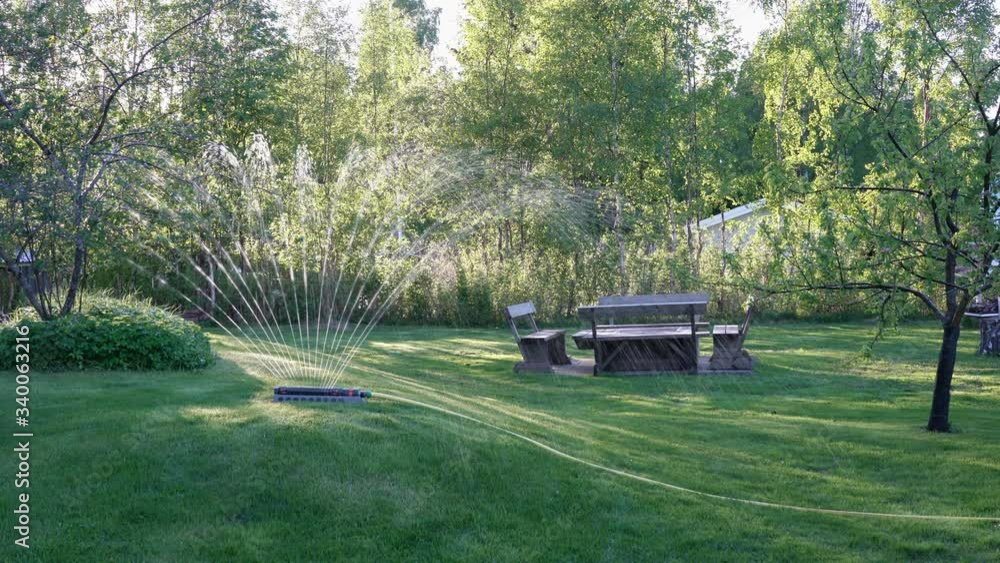 Lawn sprinkler system on garden in grass. Sprinkle sprays water on the ...