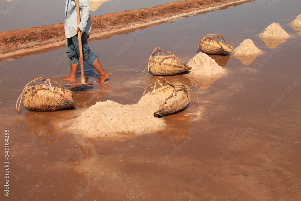 A salt farm worker harvesting salt which is the traditional and local ...