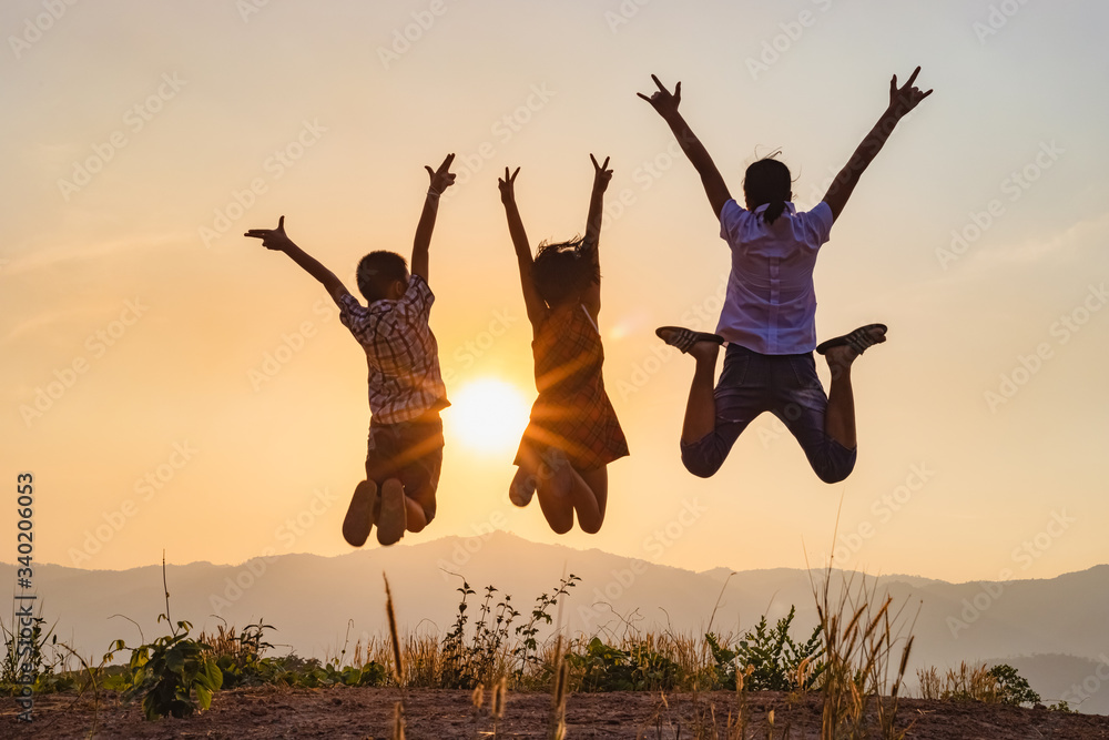 Silhouette of happy children jumping playing on mountain at sunset time ...
