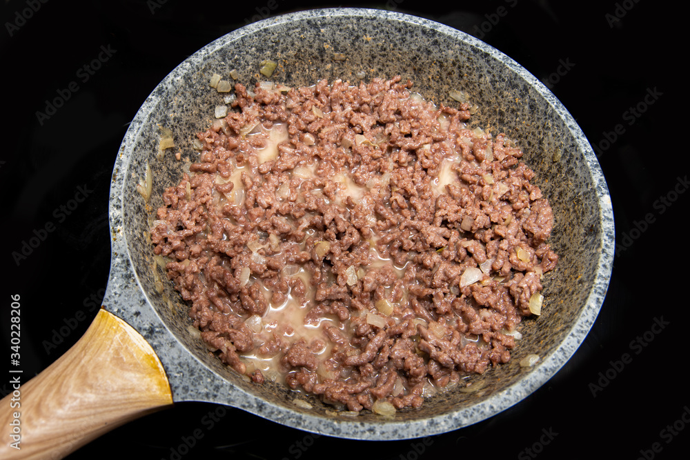 At home on an electric stove there is a gray speckled pan on which the ...