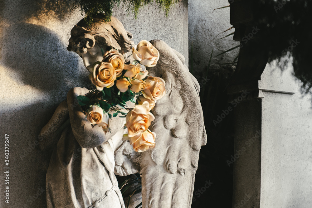 sculpture of stone granite angel with flowers on headstone in old ...