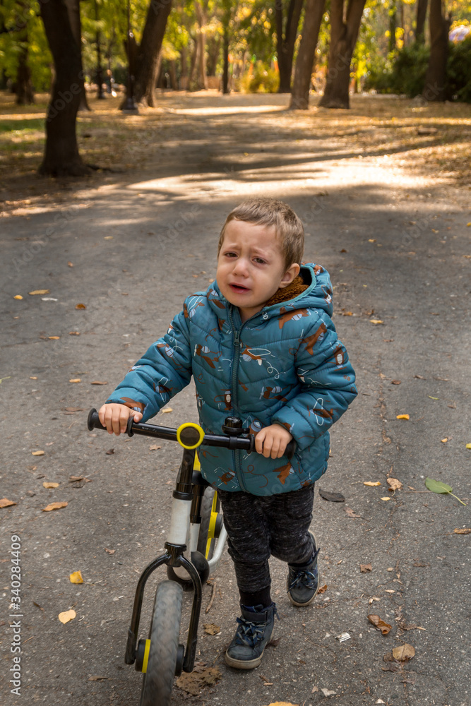 Kid hurts his arm after falling off his bicycle. Child is learning to ...