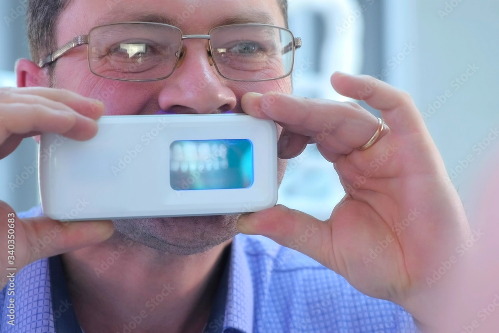 Dentist testing man's teeth using UV scanner in dentistry, portrait ...