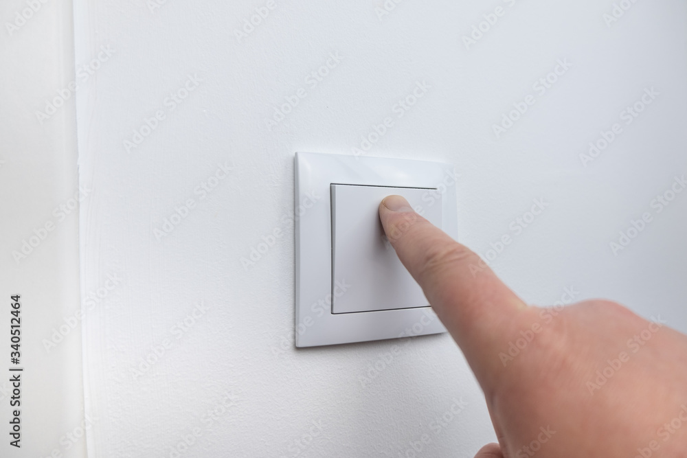Finger pressing light switch to turn off light. Modern white light ...