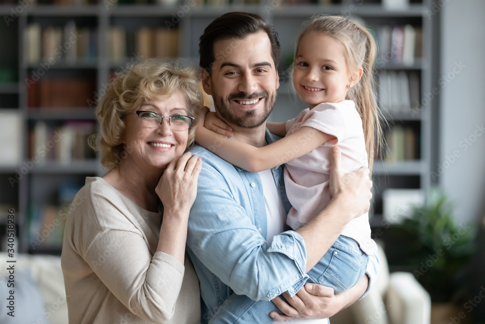 Multi generational 3 relatives portrait in living room. Father holds on ...