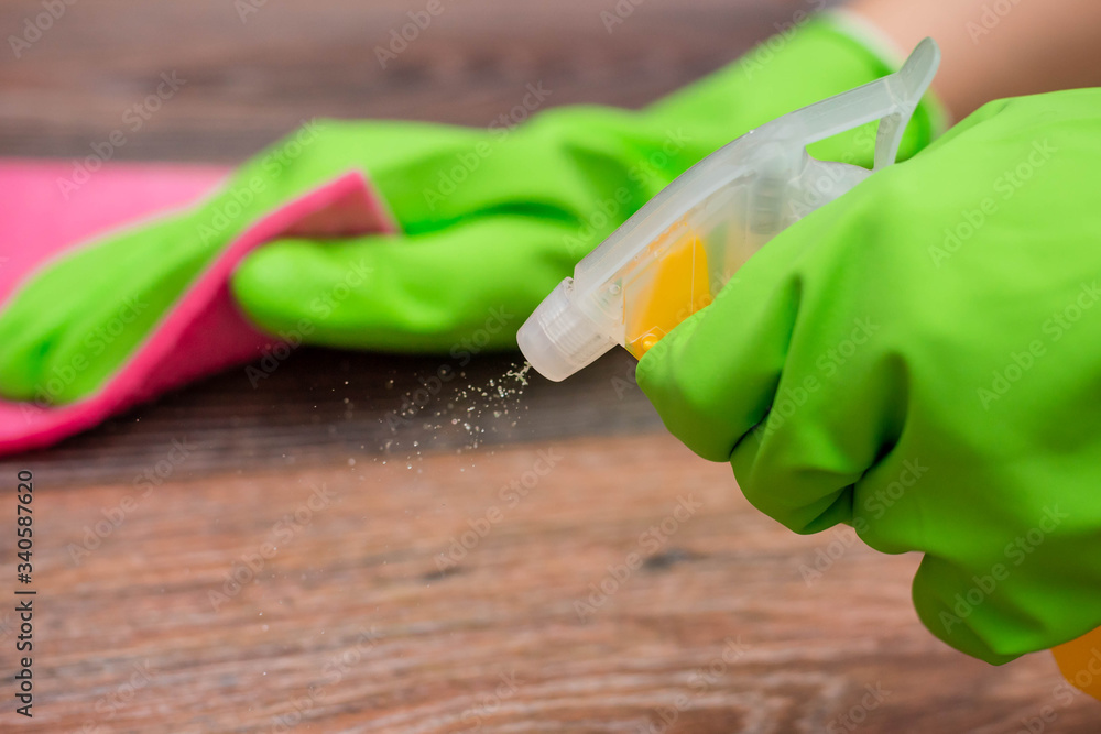 Close-up of hands in rubber gloves holding a spray bottle and rag for ...