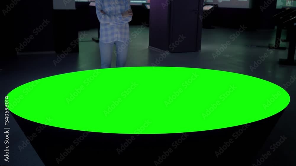 Woman looking at blank digital interactive green display of round table ...