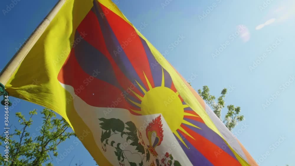 Flag of Tibet Waving in the wind wide shot, Sky and Sun and plants ...