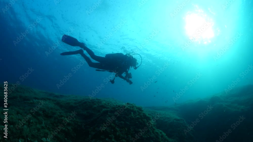 scuba divers underwater with sun beams rays and sun shine underwater ...