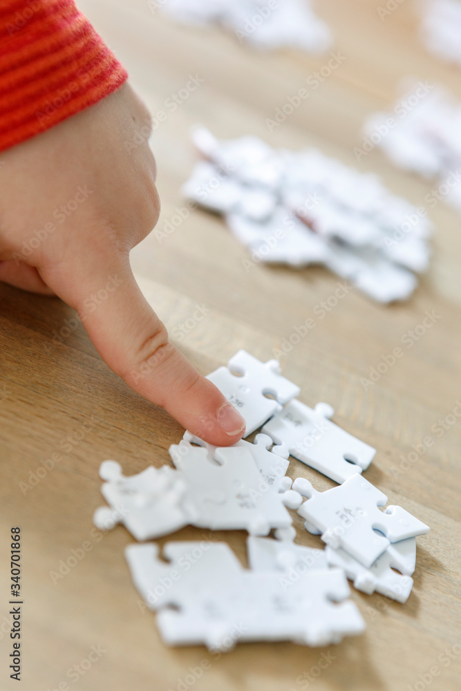 Child connecting jigsaw puzzle pieces in a living room table Stock ...