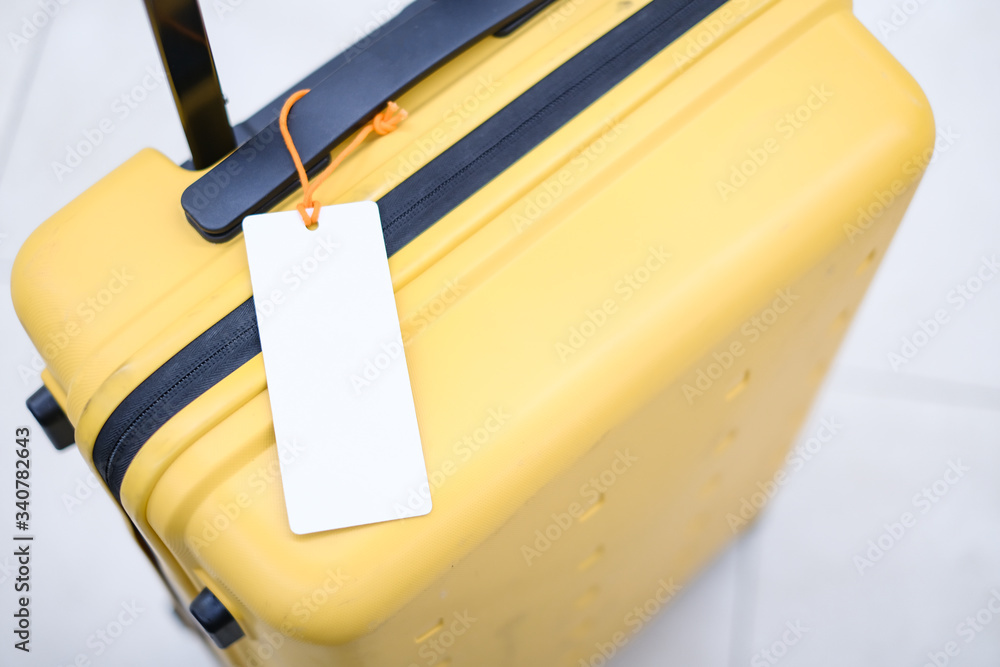 Close up mock up brand tag or name tag tied to yellow thick suitcase ...